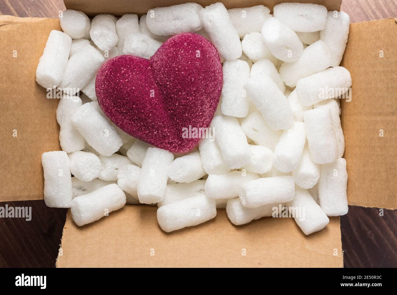 red heart in a cardboard box with styrofoam packing peanuts for concept ...
