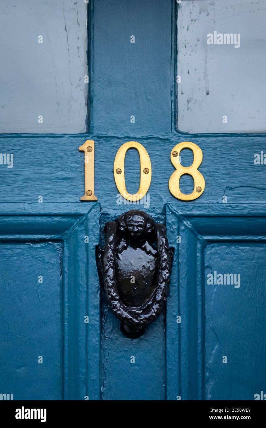 Golden metal digits form number 108 on a blue wooden front door with ...