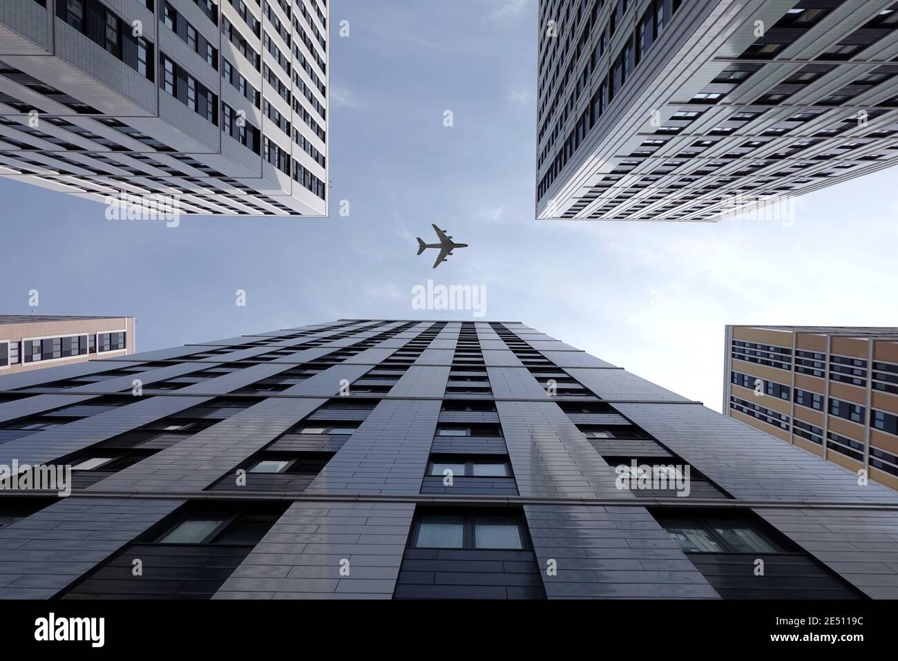 Big airplane flying high above modern city skyscraper buildings with ...