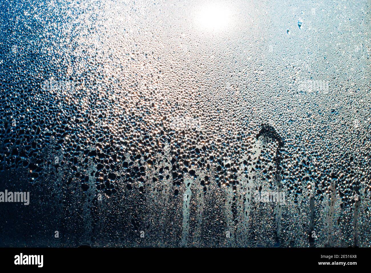 Misted window with drops of moisture that glows in the sun.Texture ...