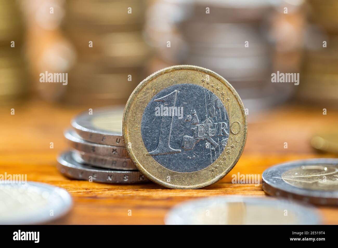 One euro coin standing on wooden table from close up Stock Photo - Alamy