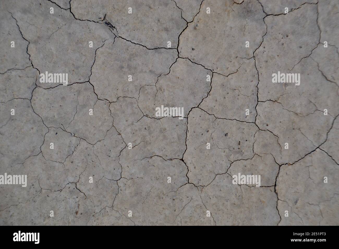 Dry cracked clay mud in full frame in grey brown colour in dry season ...