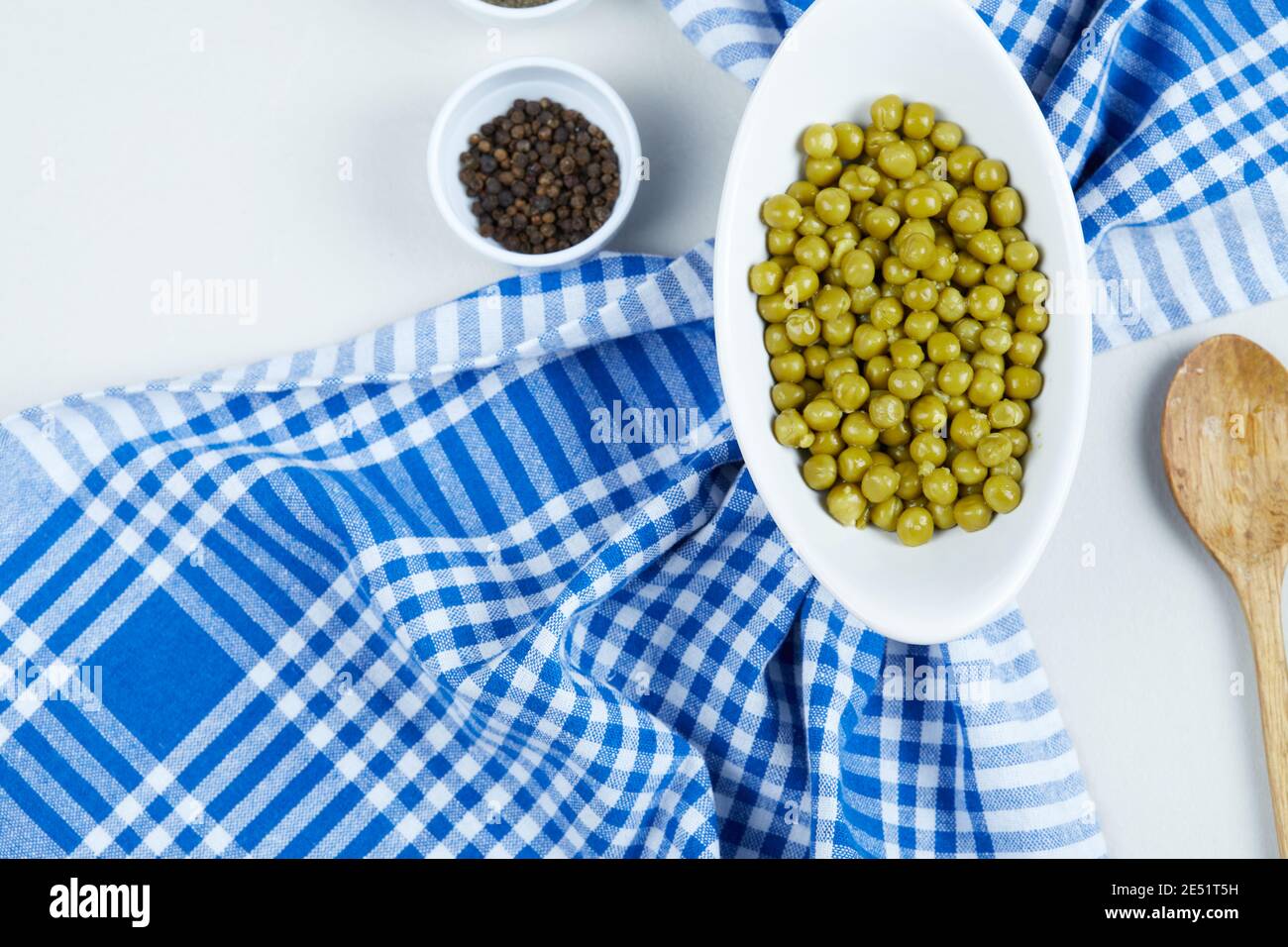 Boiled green peas in a white bowl on a white background with spices, a ...