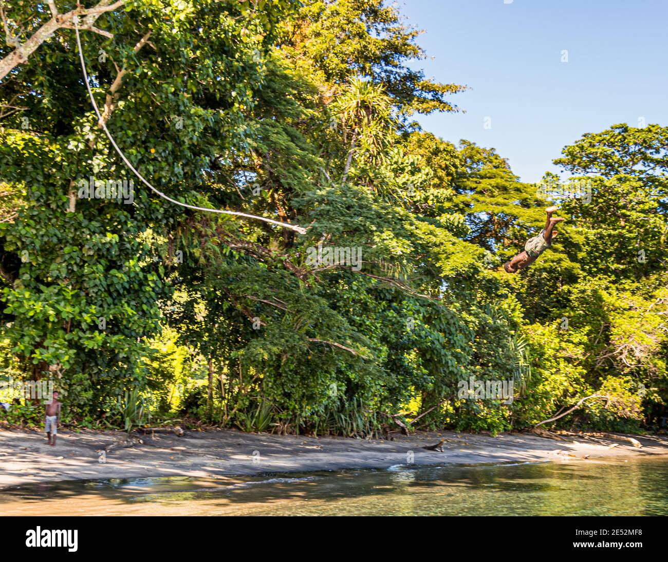 Tarzan exercise with jumping into shallow water on the beach in ...