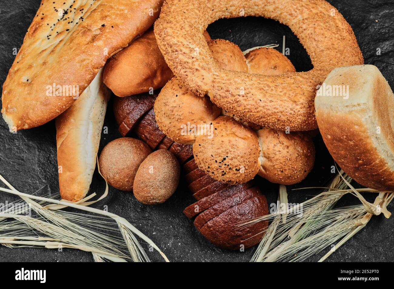 Slices of black bread, buns, bagel and baton on dark desk Stock Photo ...