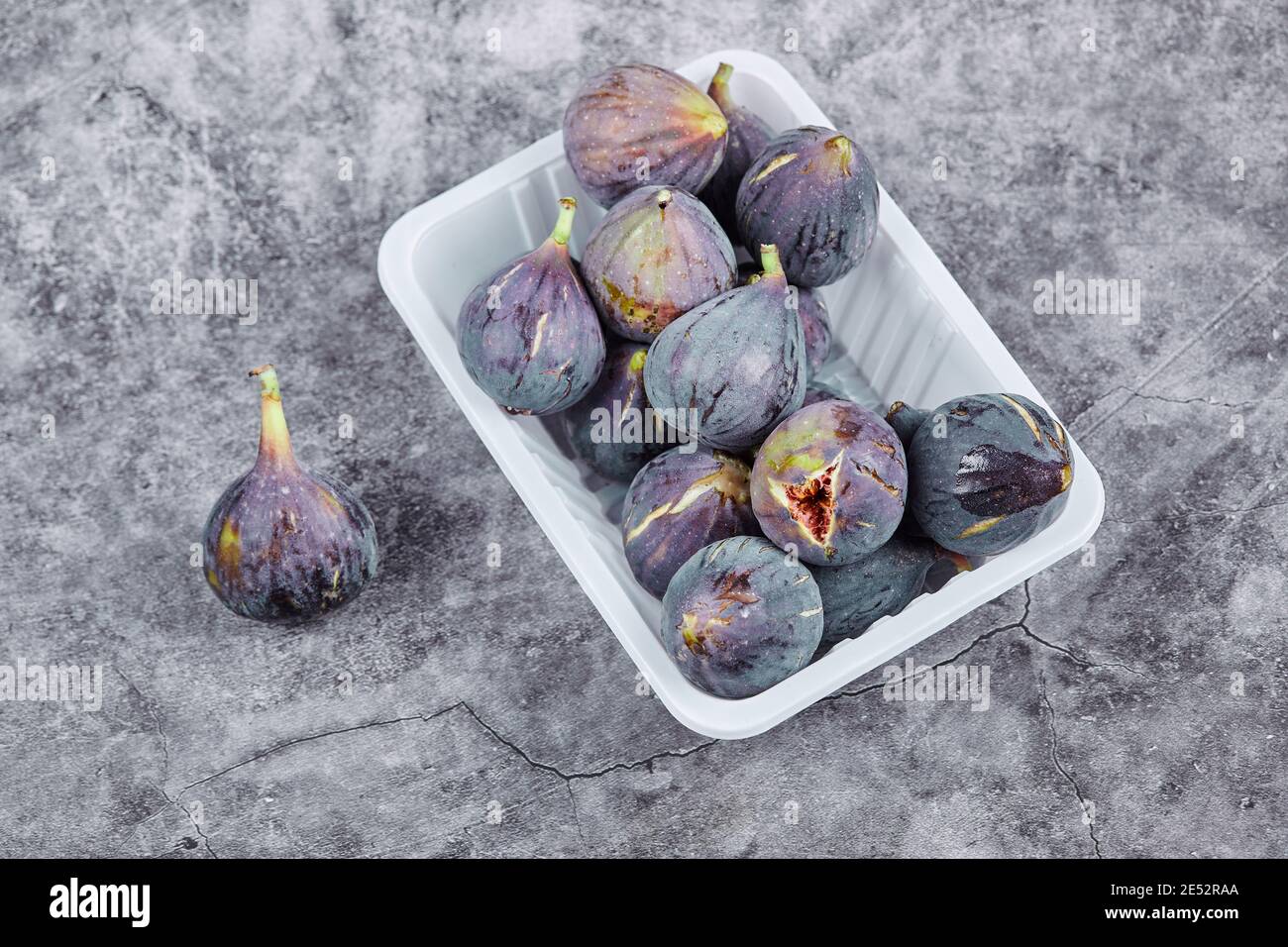 Purple figs in a white plastic container Stock Photo - Alamy