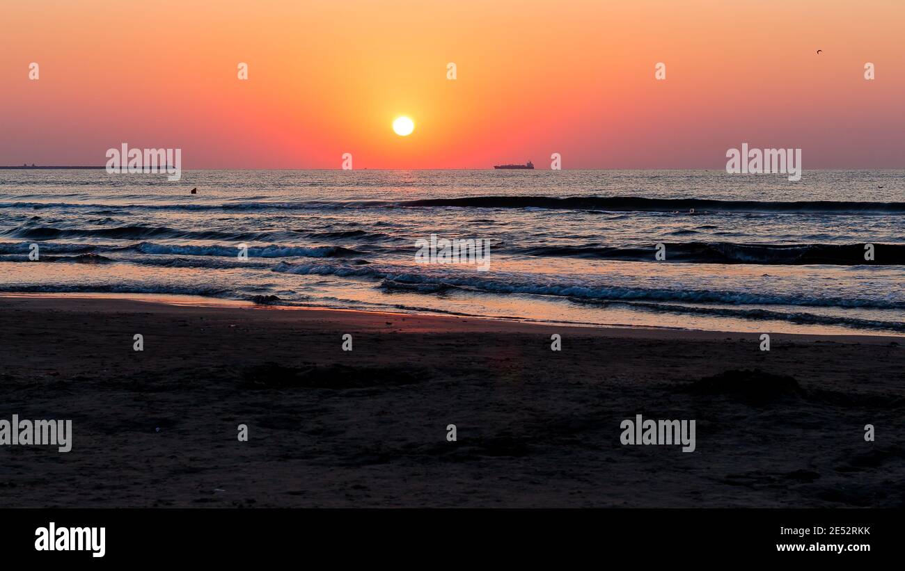 Amazing pink sunset scene with wavy sea and sandy beach Stock Photo - Alamy