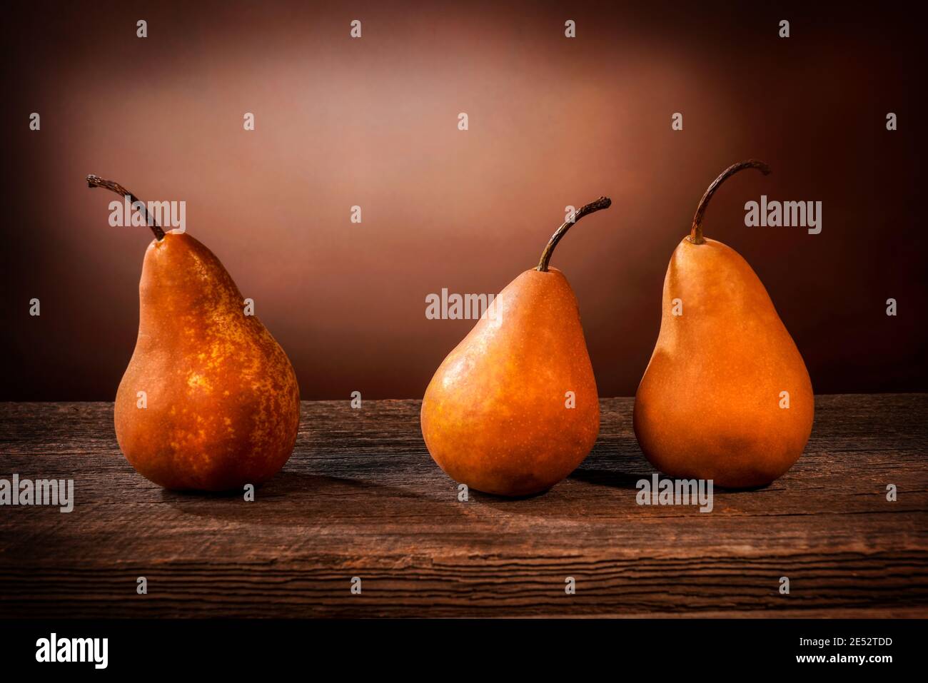 Three large yellow bosc pears on a barn wood table and grunge ...