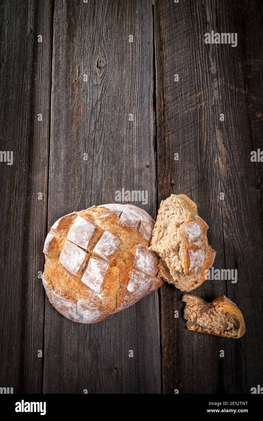 Country bread with floured crust with pieces of crumb on a barn wood ...