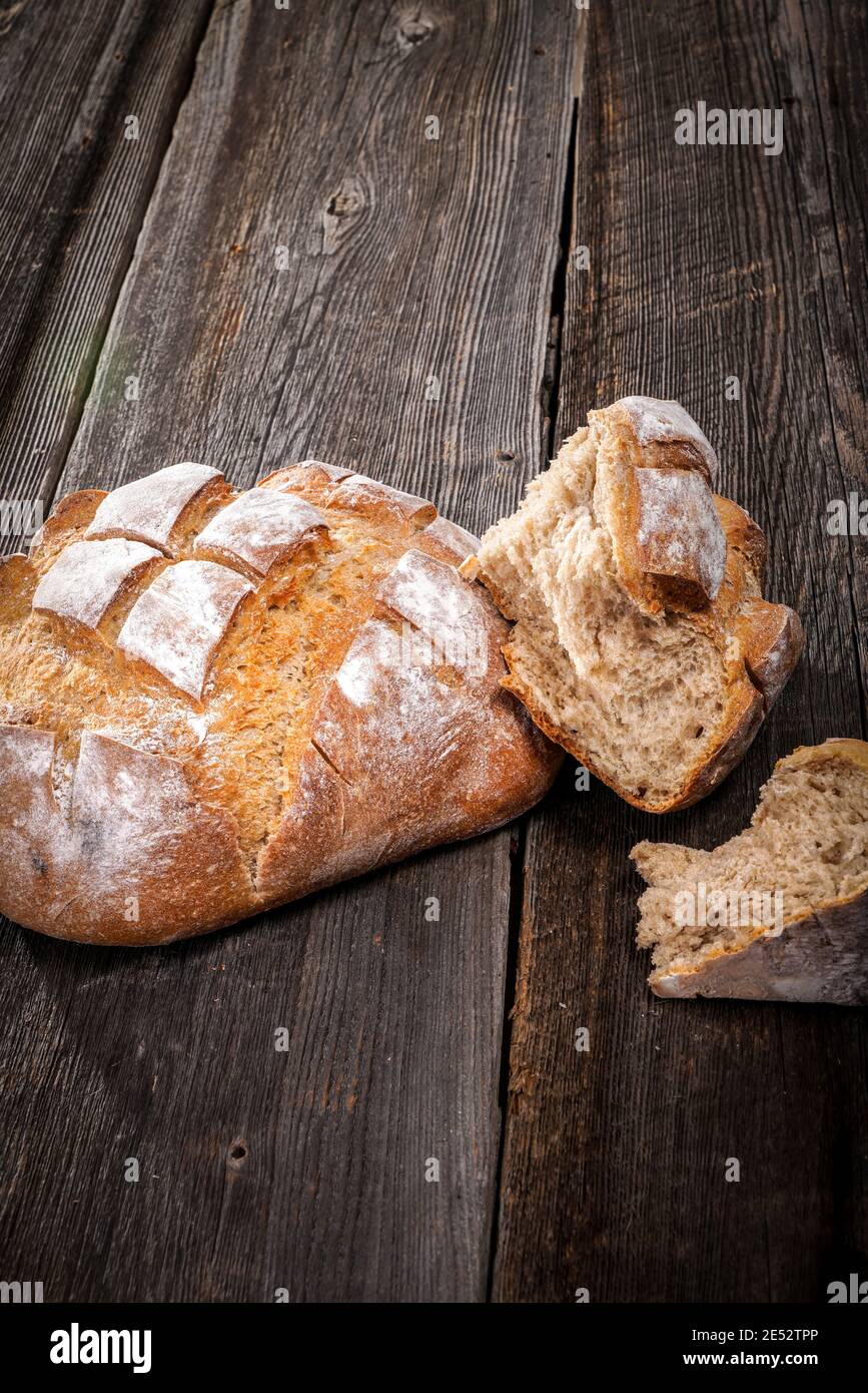 Country bread with floured crust with pieces of crumb on a barn wood ...