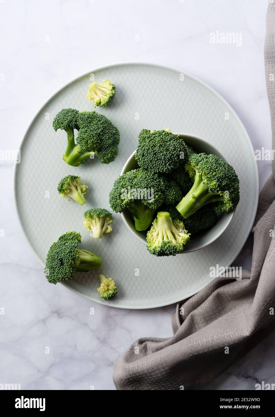 Cut broccoli on a plate placed on a marble background. View from above ...