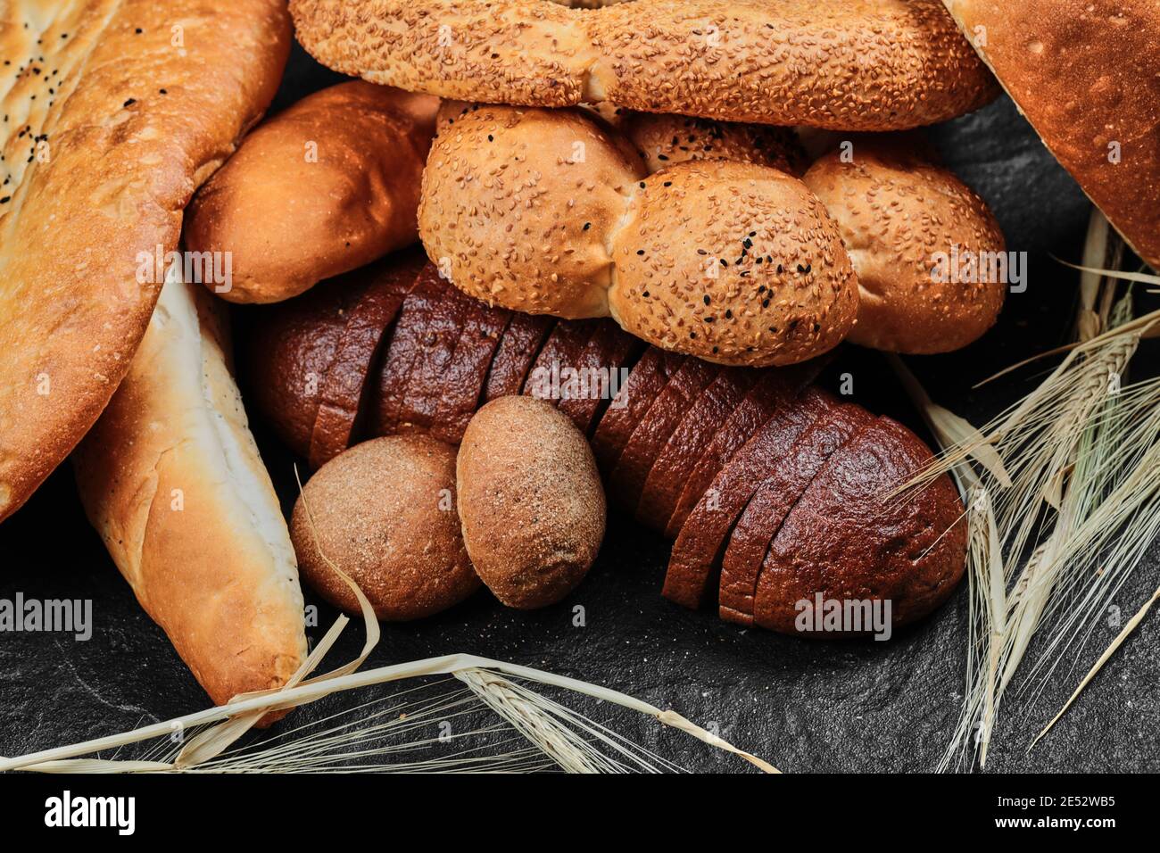 Slices of black bread, buns, bagel and baton on dark desk Stock Photo ...