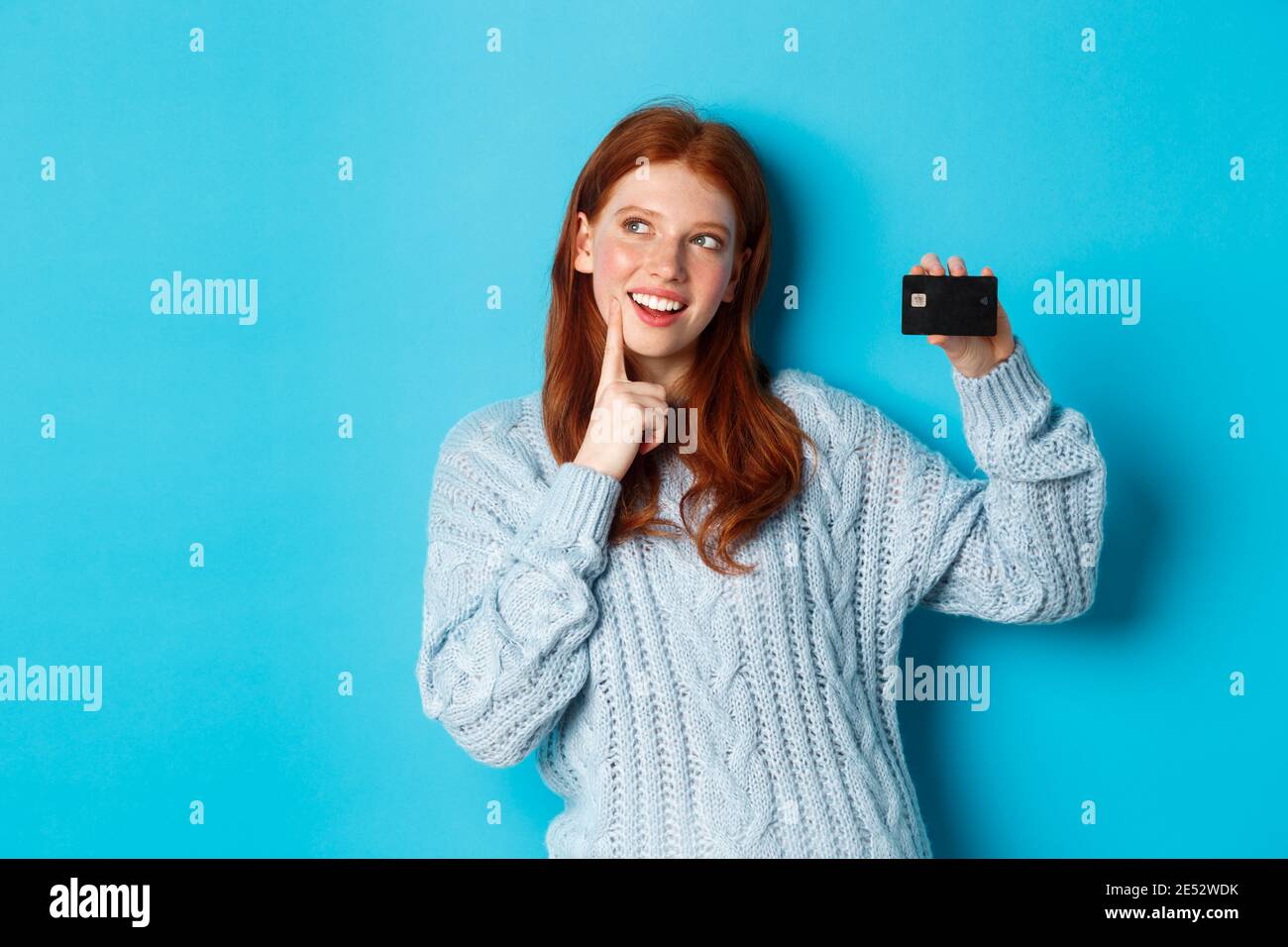 Image of thoughtful redhead girl thinking about shopping, showing ...