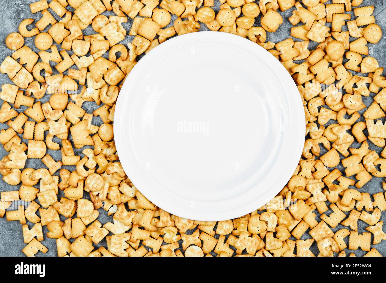 Scattered alphabet crackers around a empty plate Stock Photo - Alamy