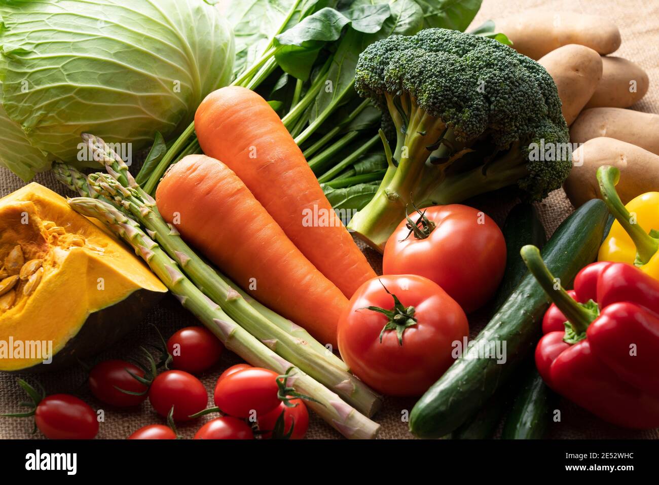 A large variety of fresh vegetables set against a background of burlap ...