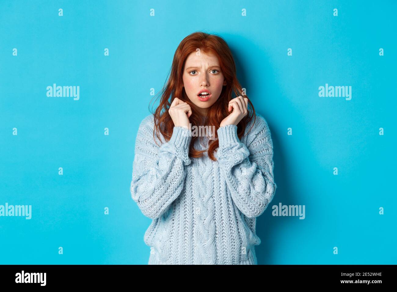 Image of scared teenage girl with red hair, jumping startled and ...