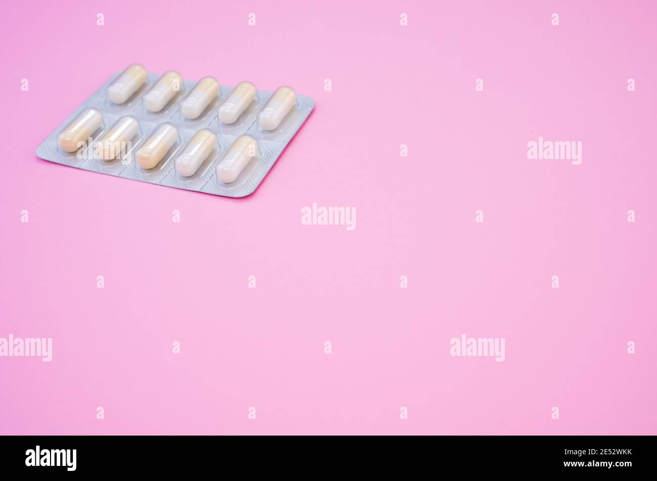 Isolated shot of the medicine capsules in a pad on a pink background ...
