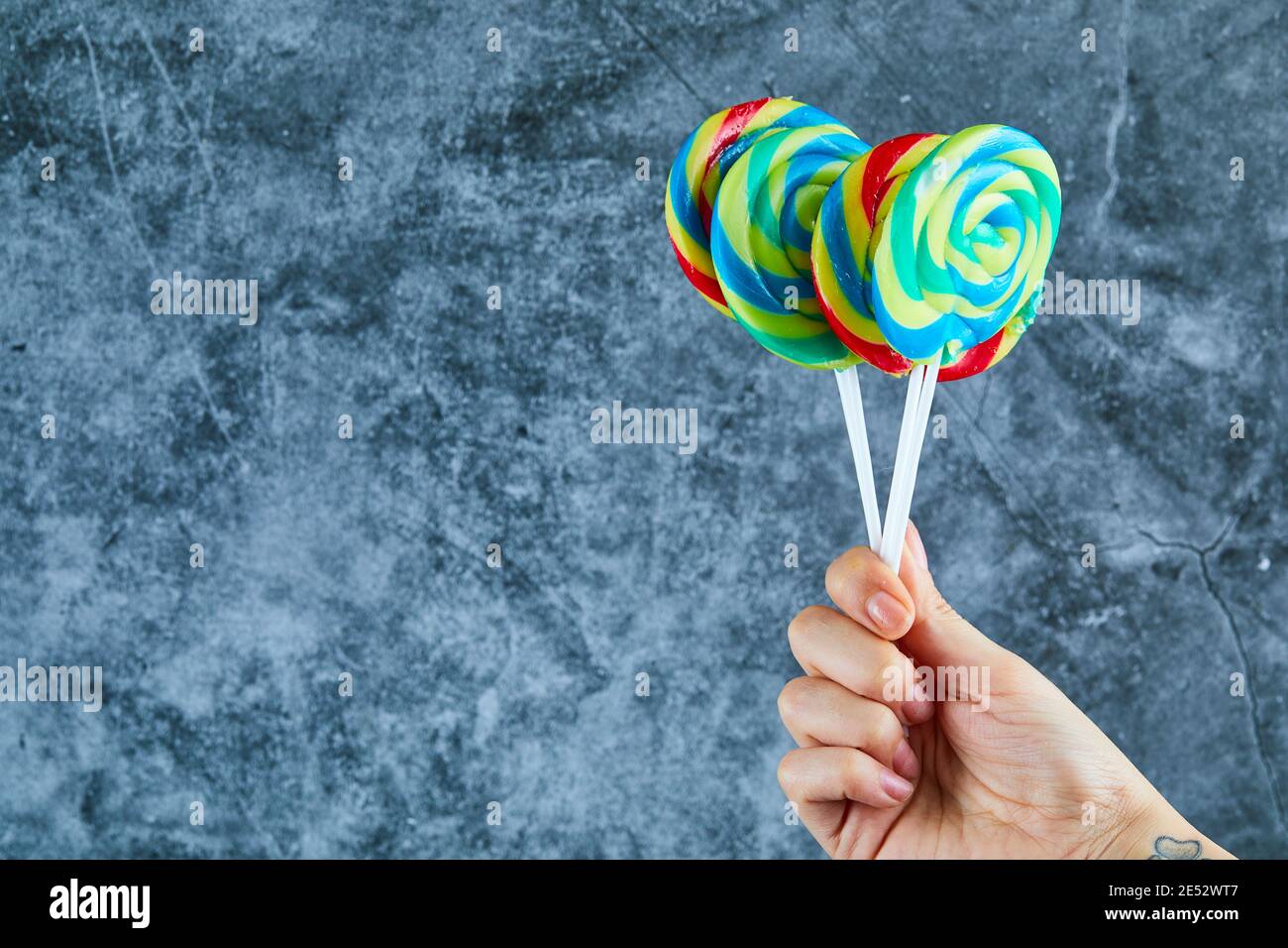 Hand holding colorful lollipops on marble background Stock Photo - Alamy