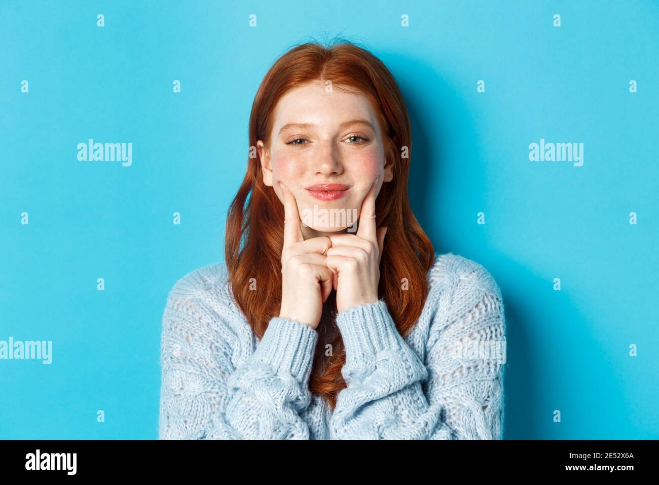 Close-up of cute and silly girl with red hair poking cheeks, showing ...