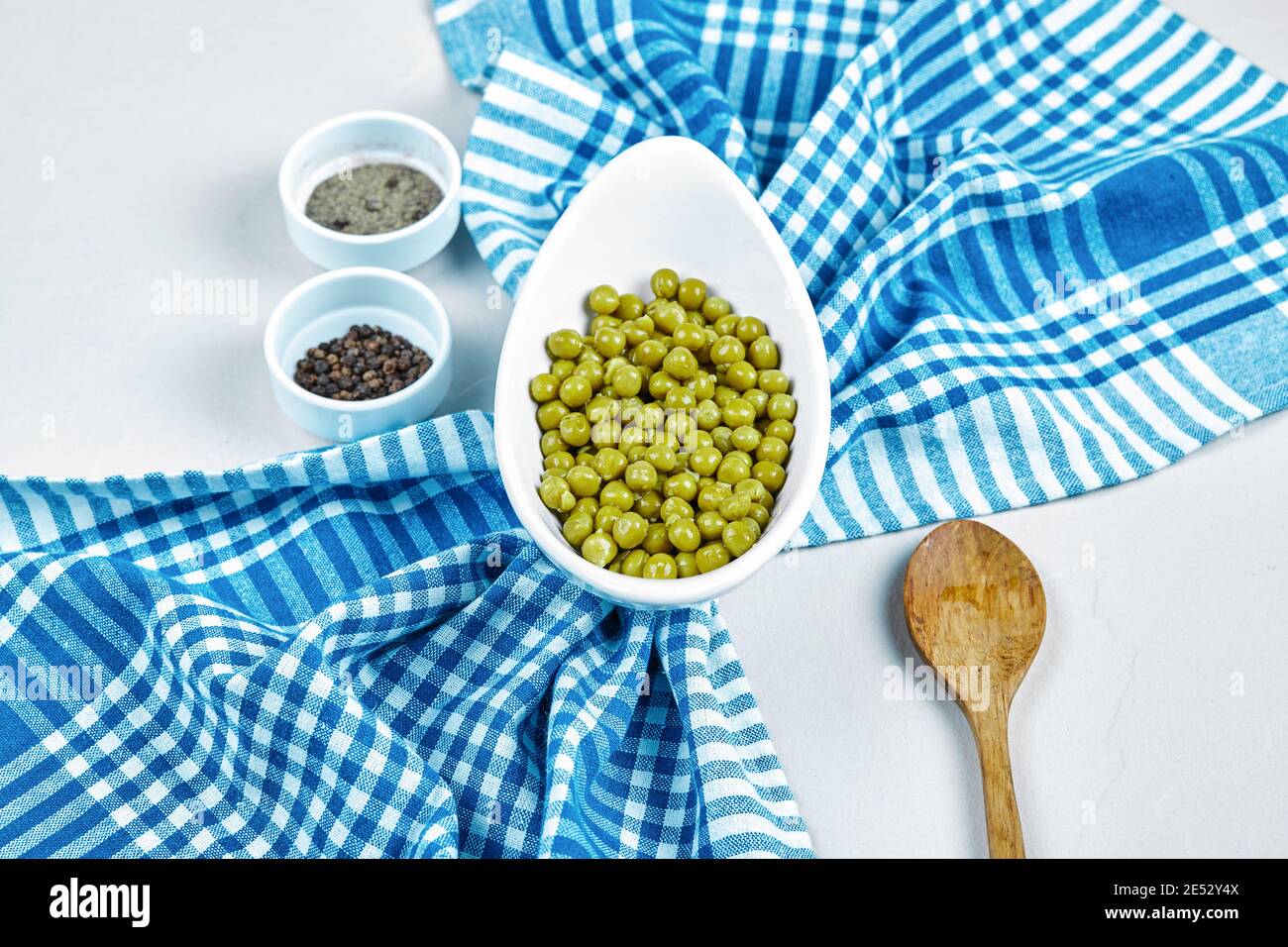 Boiled green peas in a white bowl on a white background with spices, a ...
