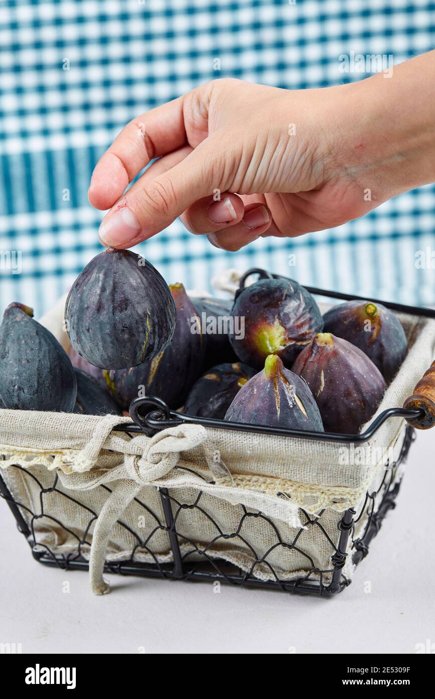 Hand holding a fig from the basket on a white background Stock Photo ...