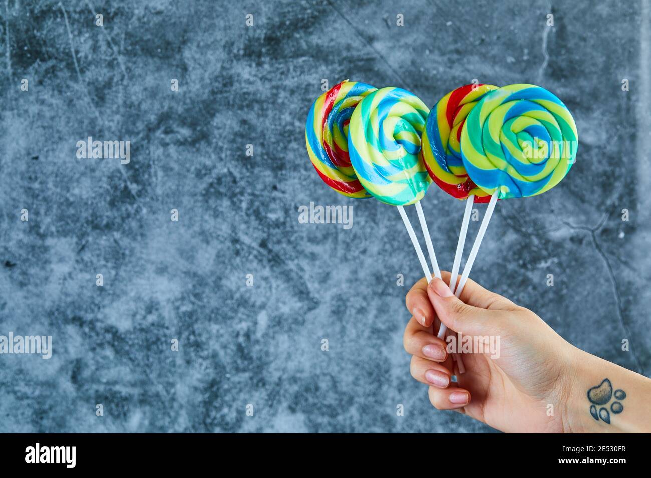 Hand holding colorful lollipops on marble background Stock Photo - Alamy