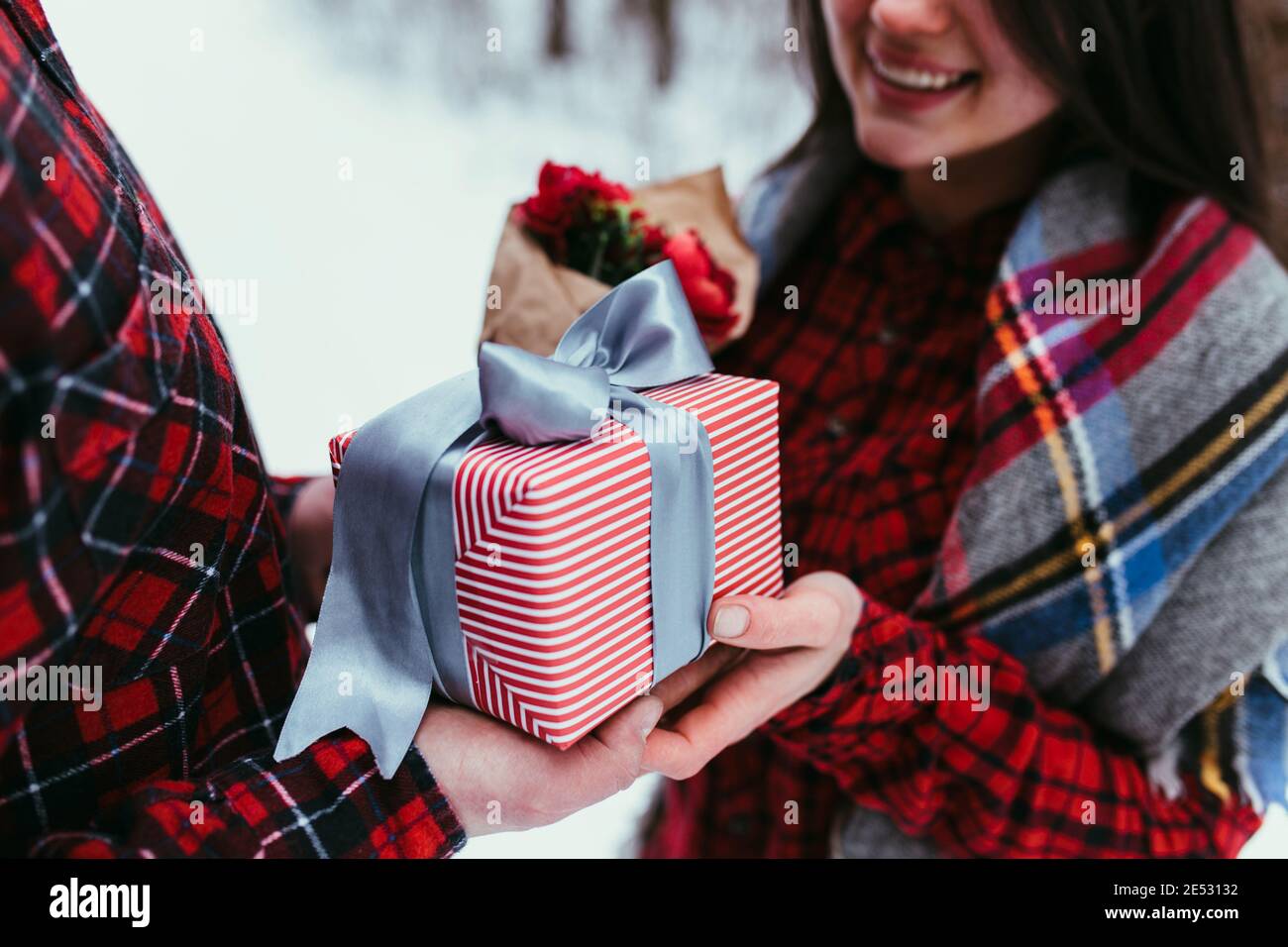 Hands giving a gift box with ribbon. Blurred background Stock Photo - Alamy