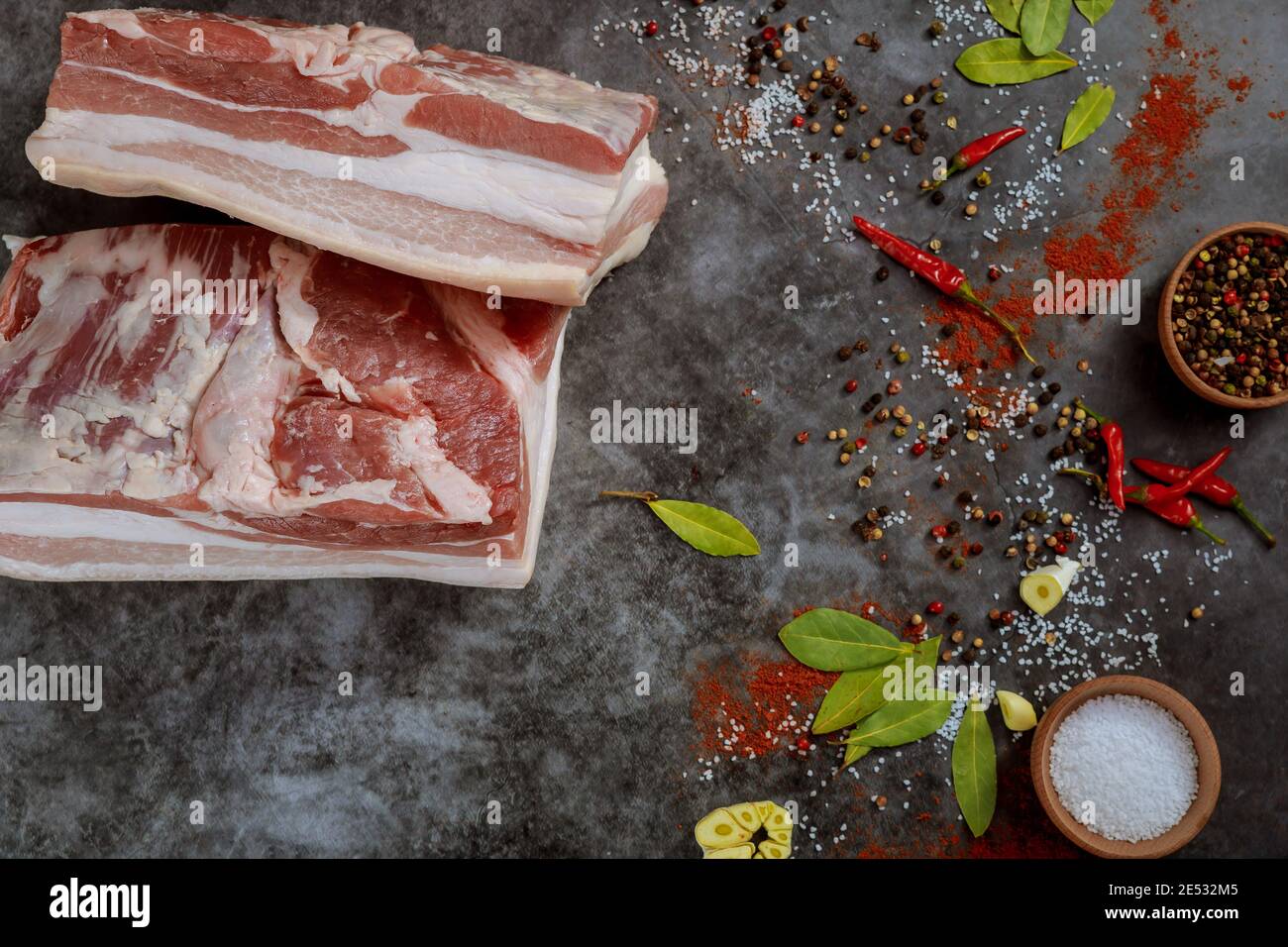 Fresh raw pork belly pieces on dark background with spices and herbs ...