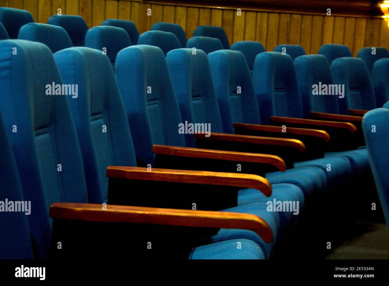 Rows of blue colored cushioned seats with arm rests at convention hall ...