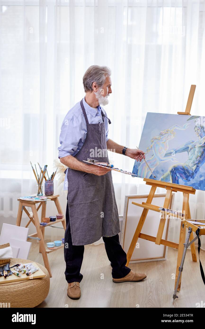 artist immersed in the creation of art, painting canvas on easel ...