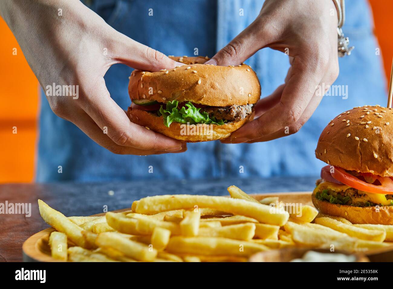 A woman hand holding cheeseburger with fry potato, ketchup, mayonnaise ...