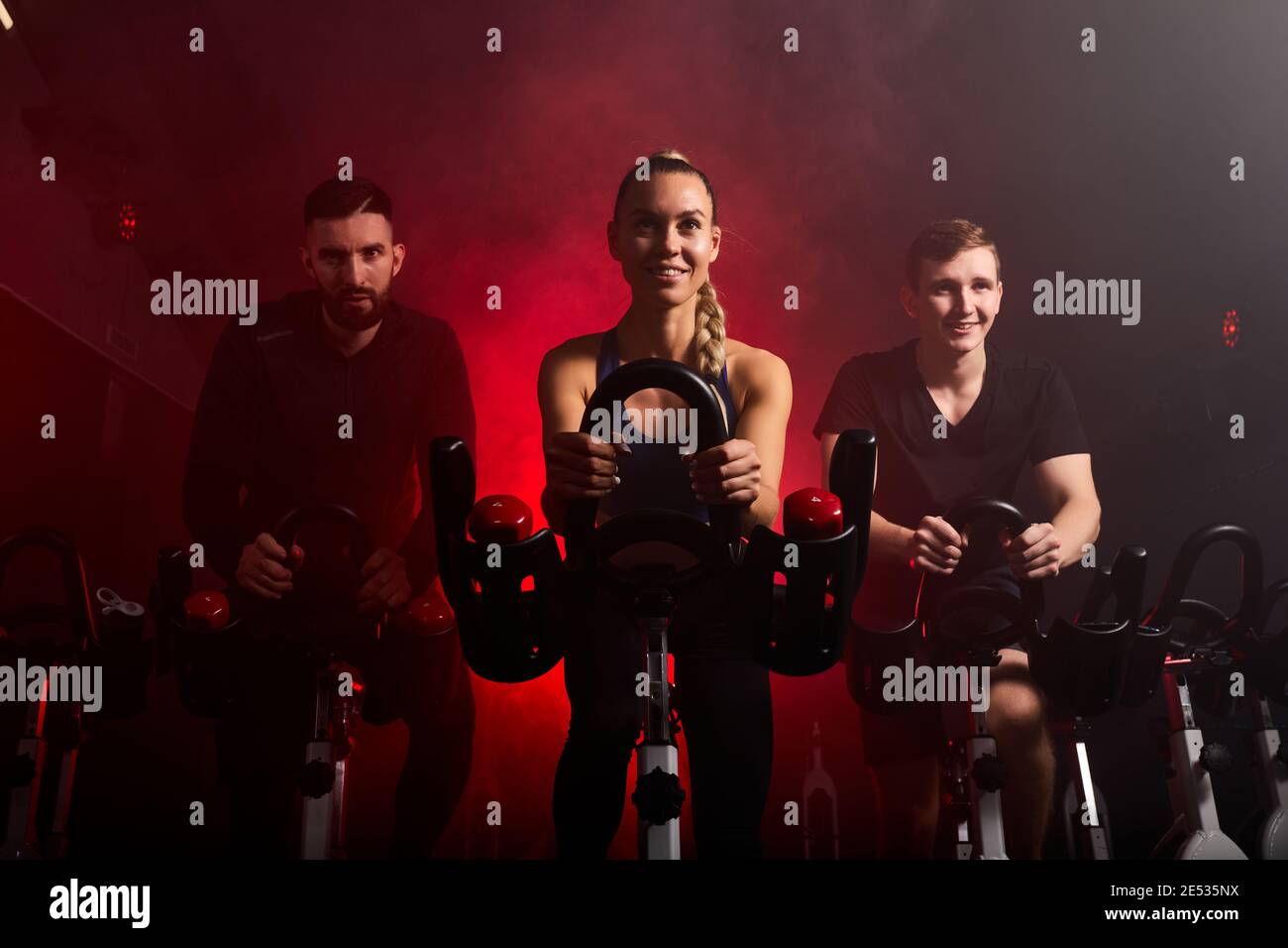 fit people riding exercise bikes in gym, enjoying workout time, in ...