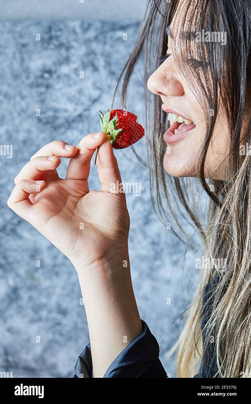 Woman eating fresh red strawberry on marble background Stock Photo - Alamy