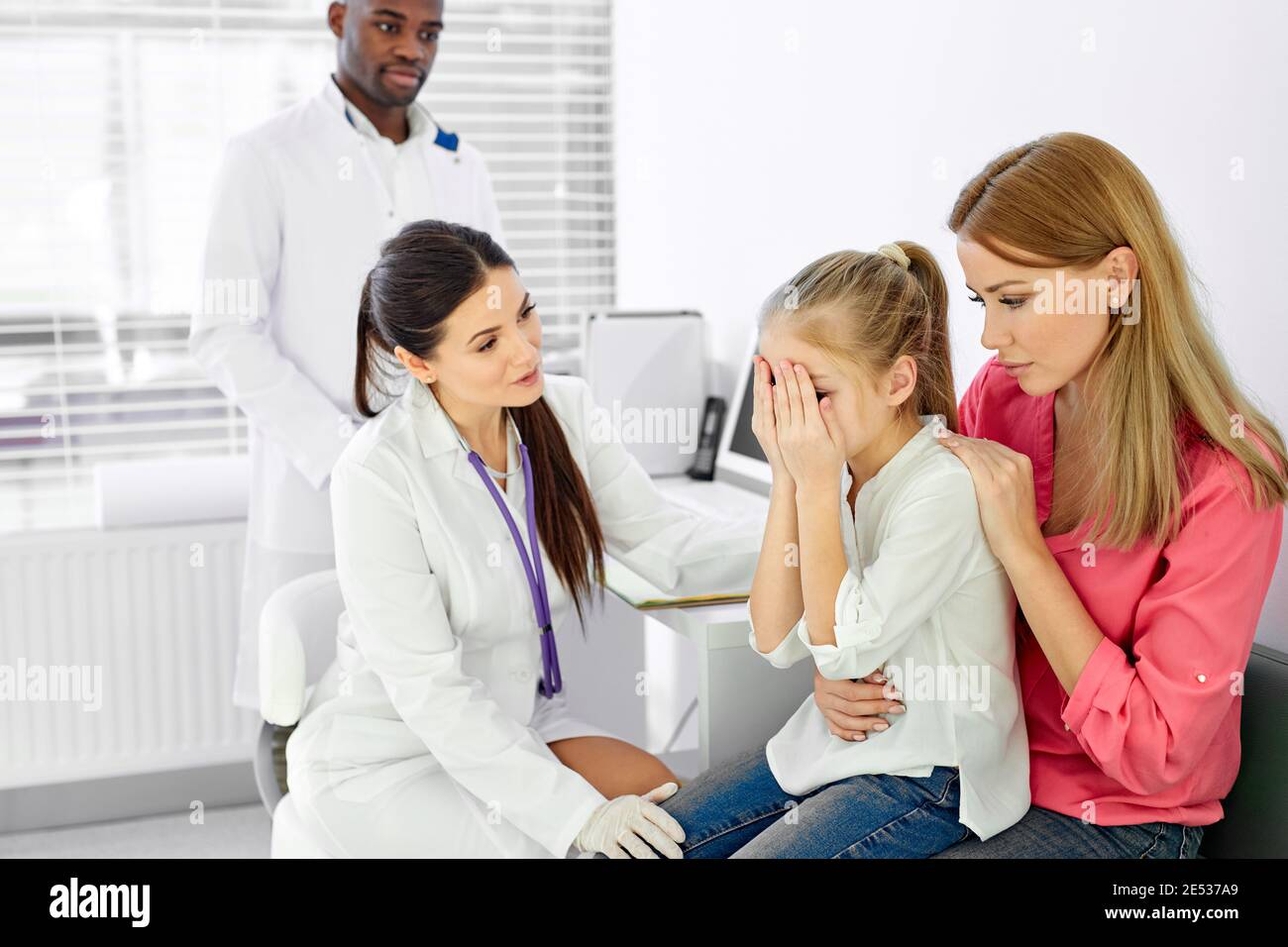 female doctor general practitioner talks and amuses child before ...