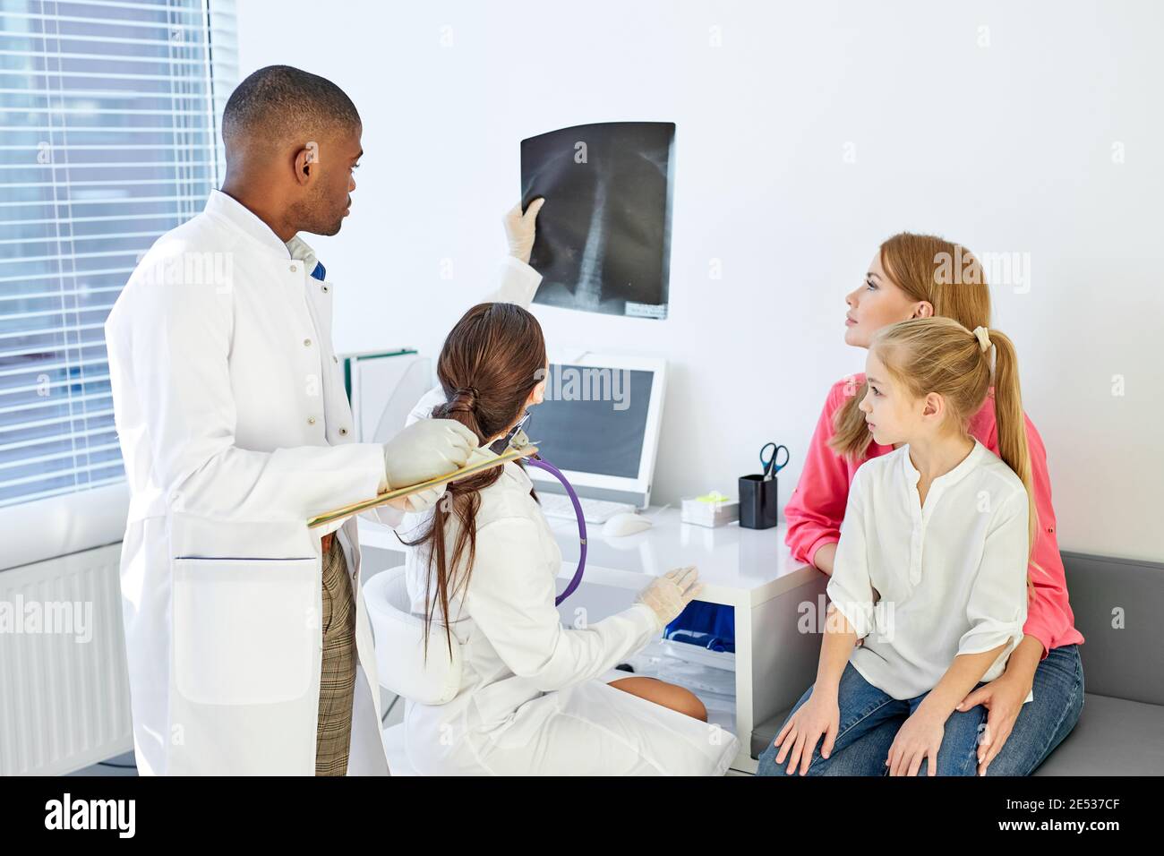 doctor and assistant showing back x-ray to sick patients, explaining ...
