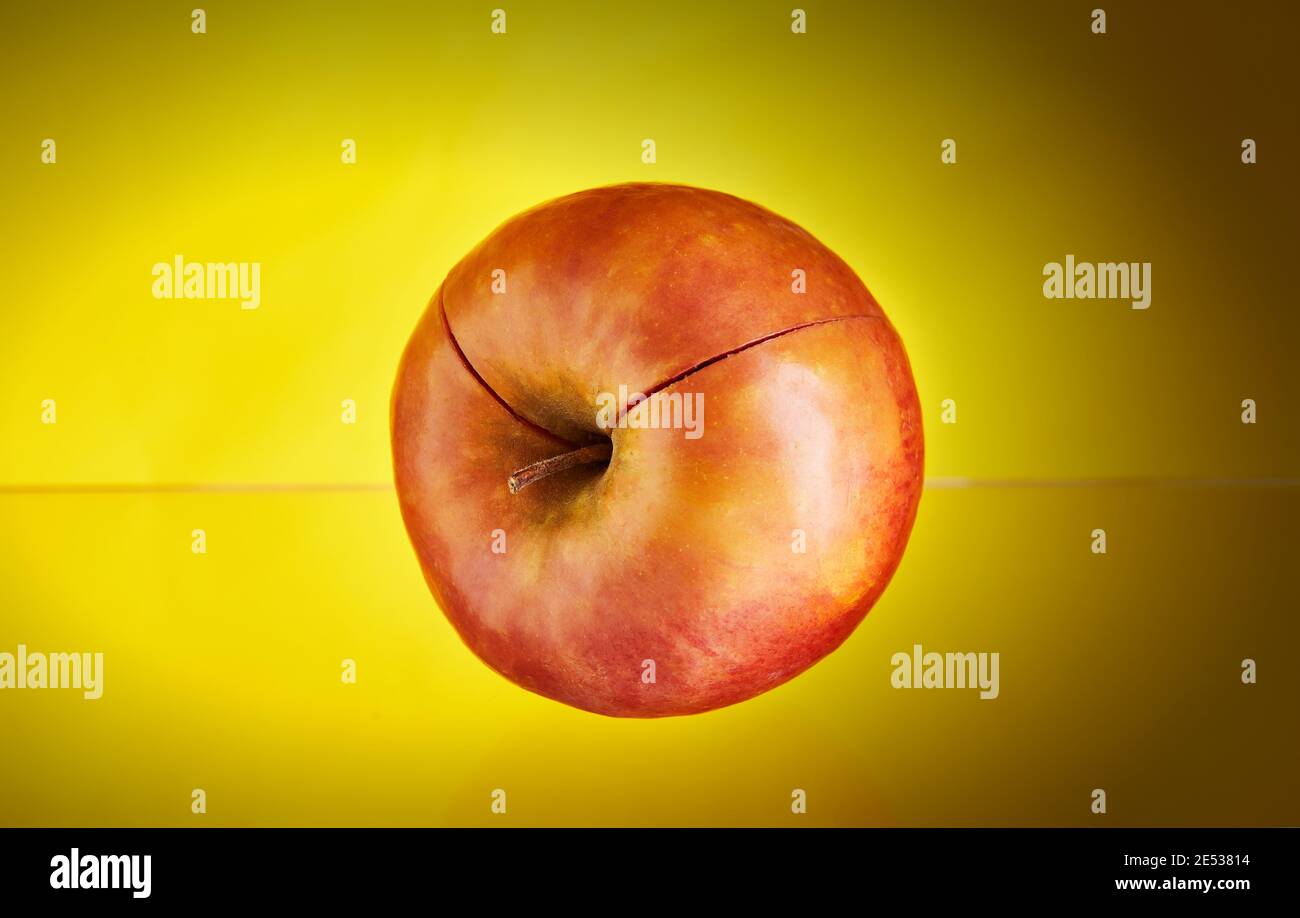 Apple with red flesh inside with a cut out wedge. Yellow background ...