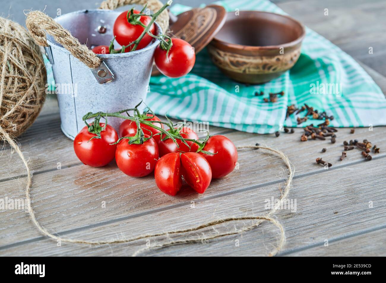 Bucket of tomatoes and half cut tomato on wooden table with empty bowl Stock Photo - Alamy