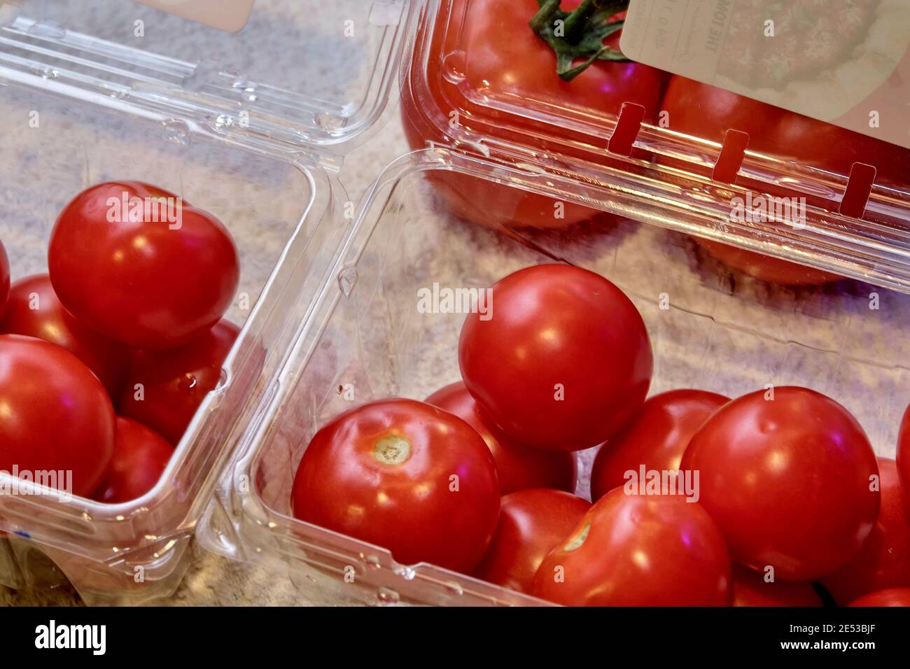 Fresh supermarket tomatoes packaged in clear plastic boxes with lids ...