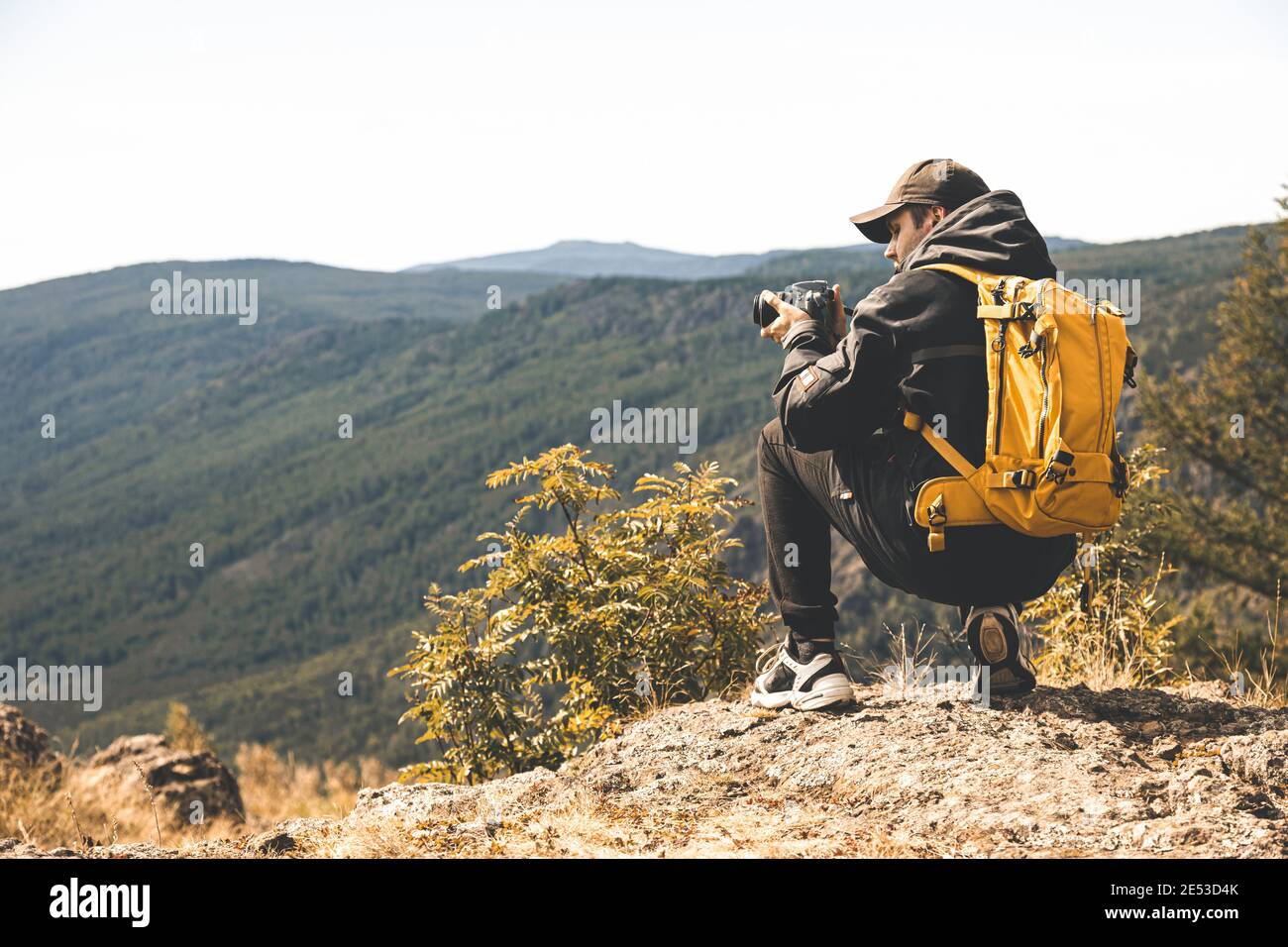 A man with a yellow backpack goes hiking in the mountains and takes ...