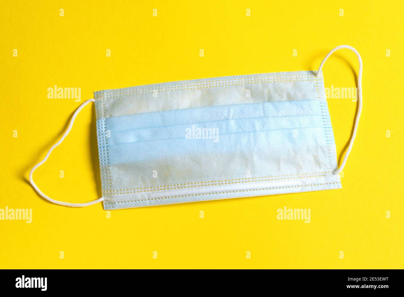 Medical hygienic protective face ear-loop mask on yellow background ...