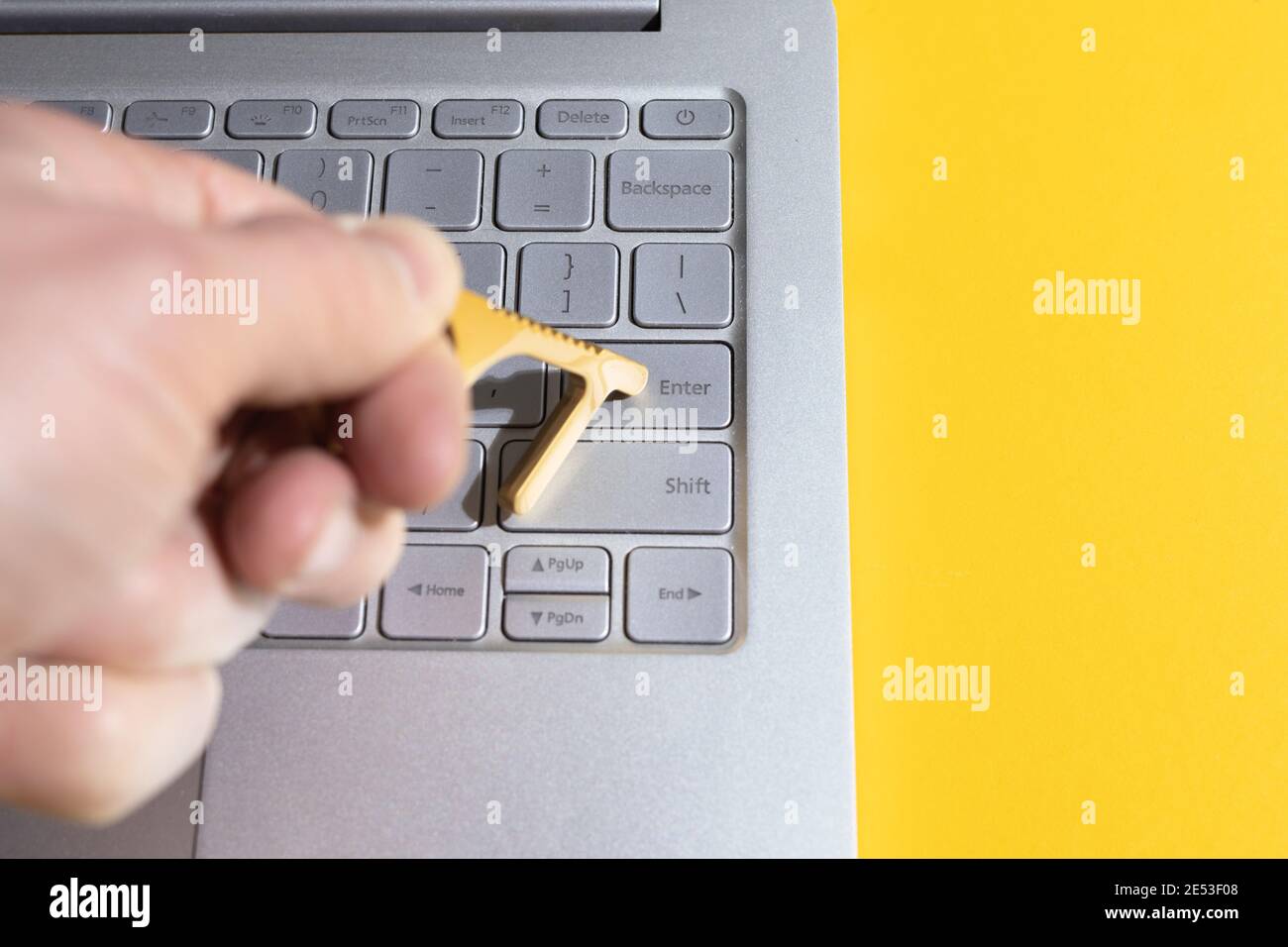 man using contactless tool to press laptop button and prevent spread of ...