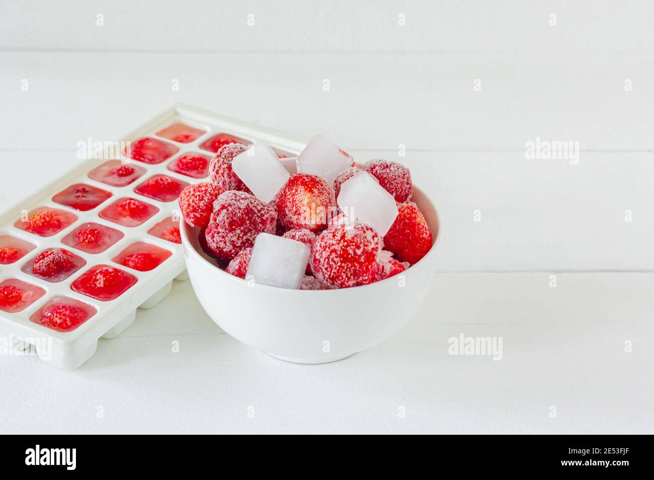 Fresh ripe strawberries frozen in ice cubes on white background ...