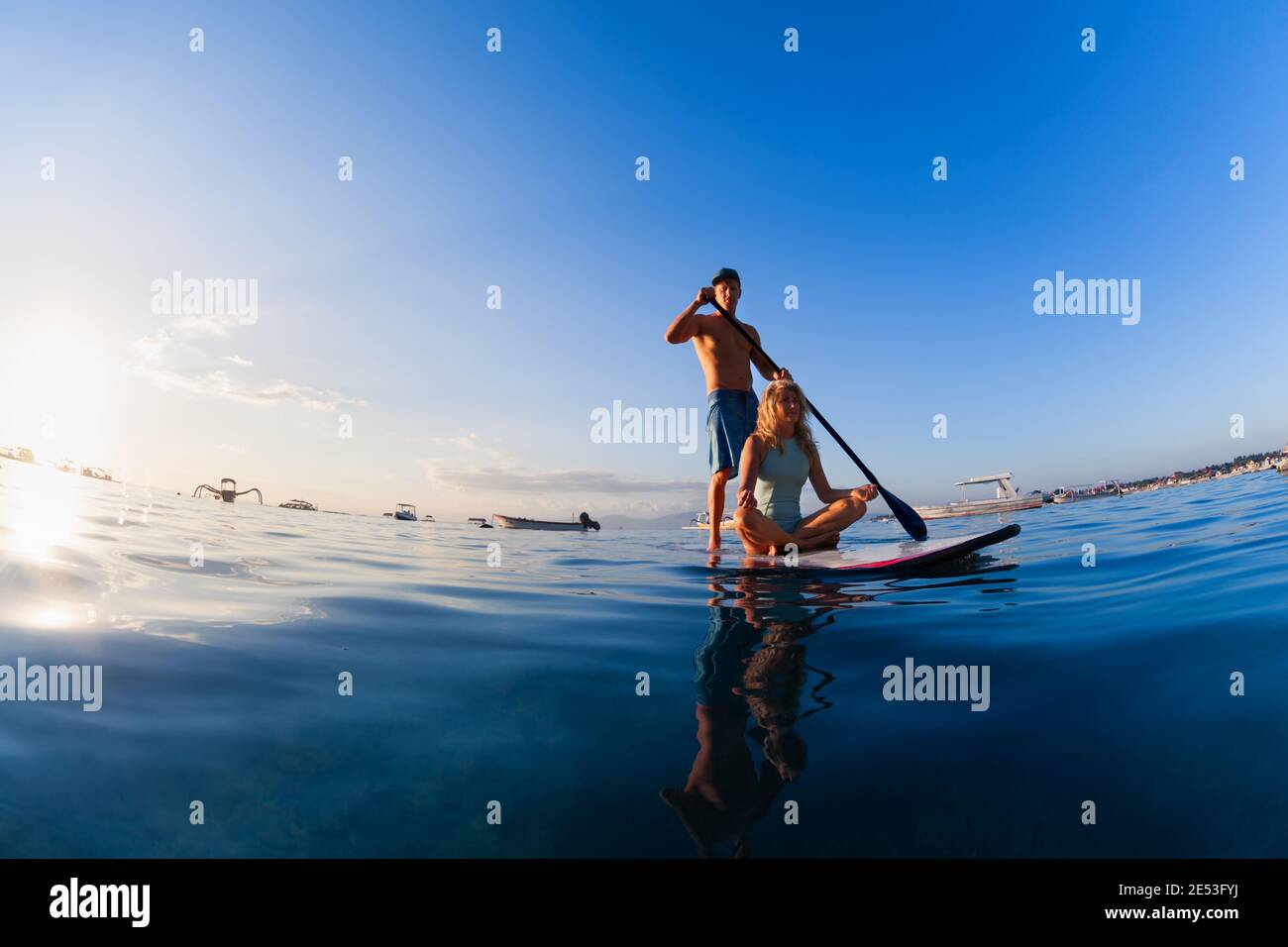Young happy couple have fun on stand up paddleboard. Active paddle ...