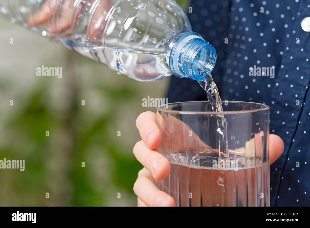 boy is pouring water from the plastic bottle into the glass on wooden table Stock Photo - Alamy