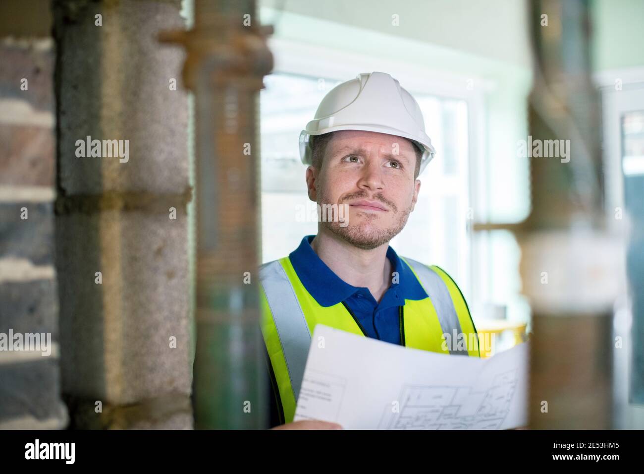 Architect Wearing Hard Hat Inside House Being Renovated Studying Plans ...