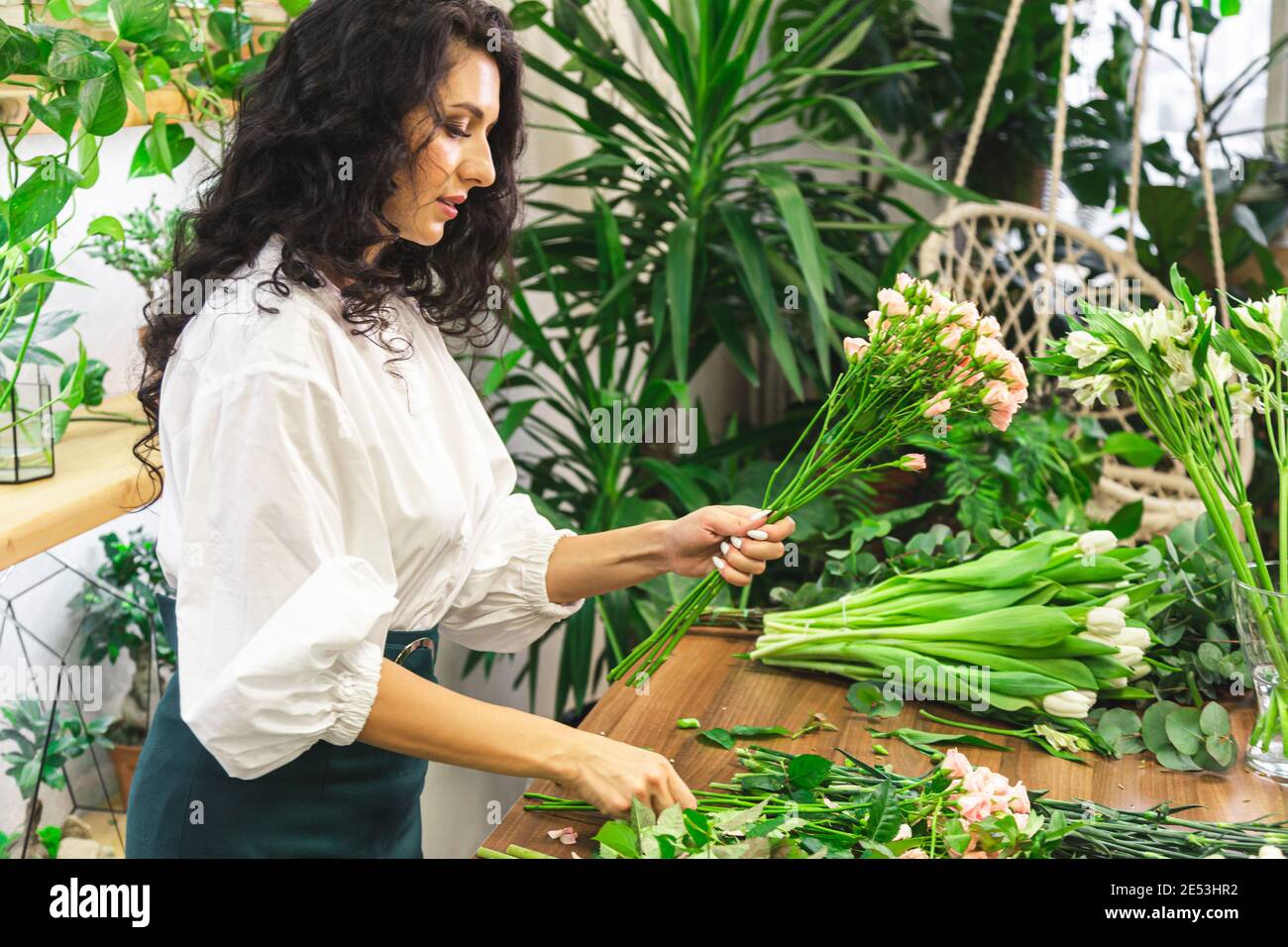 Attractive young woman florist is working in a flower shop Stock Photo ...