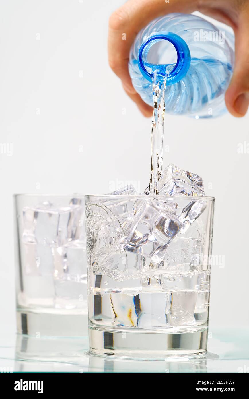 Pouring clean drinking water from blue plastic bottle into glass on ...