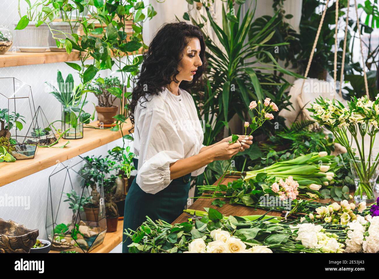 Attractive young woman florist is working in a flower shop Stock Photo ...