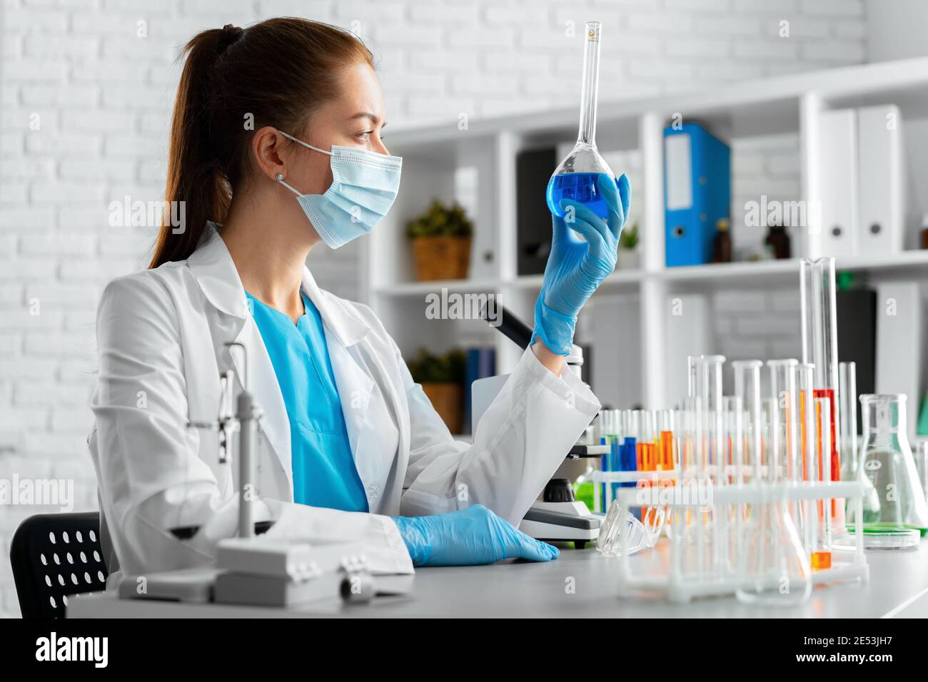 Woman scientist or laboratory worker holding glass flask with chemical ...