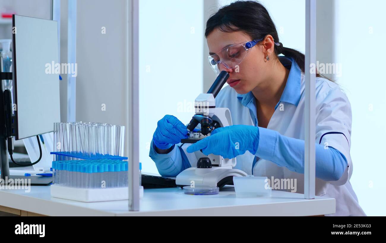 Scientist placing a slide on specimen stage of a laboratory microscope ...